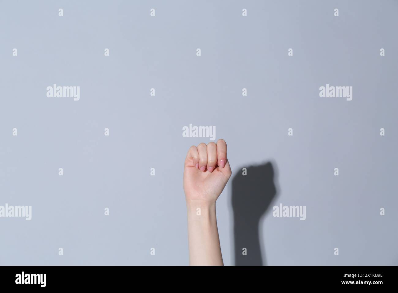 SOS gesture. Woman showing signal for help on light grey background ...