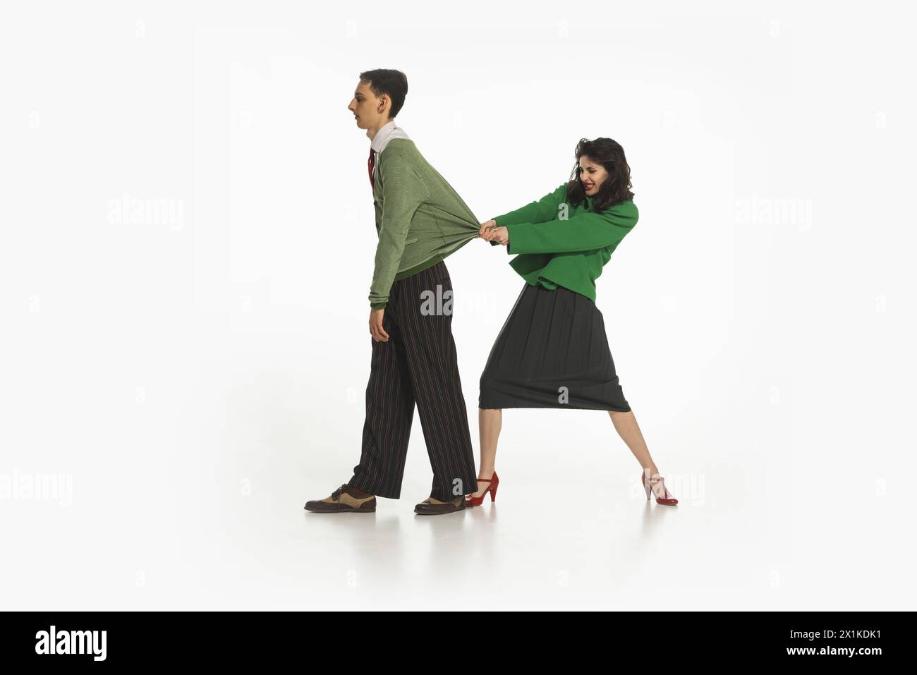 Emotionless young man walking away while woman pulling his with sweater ...