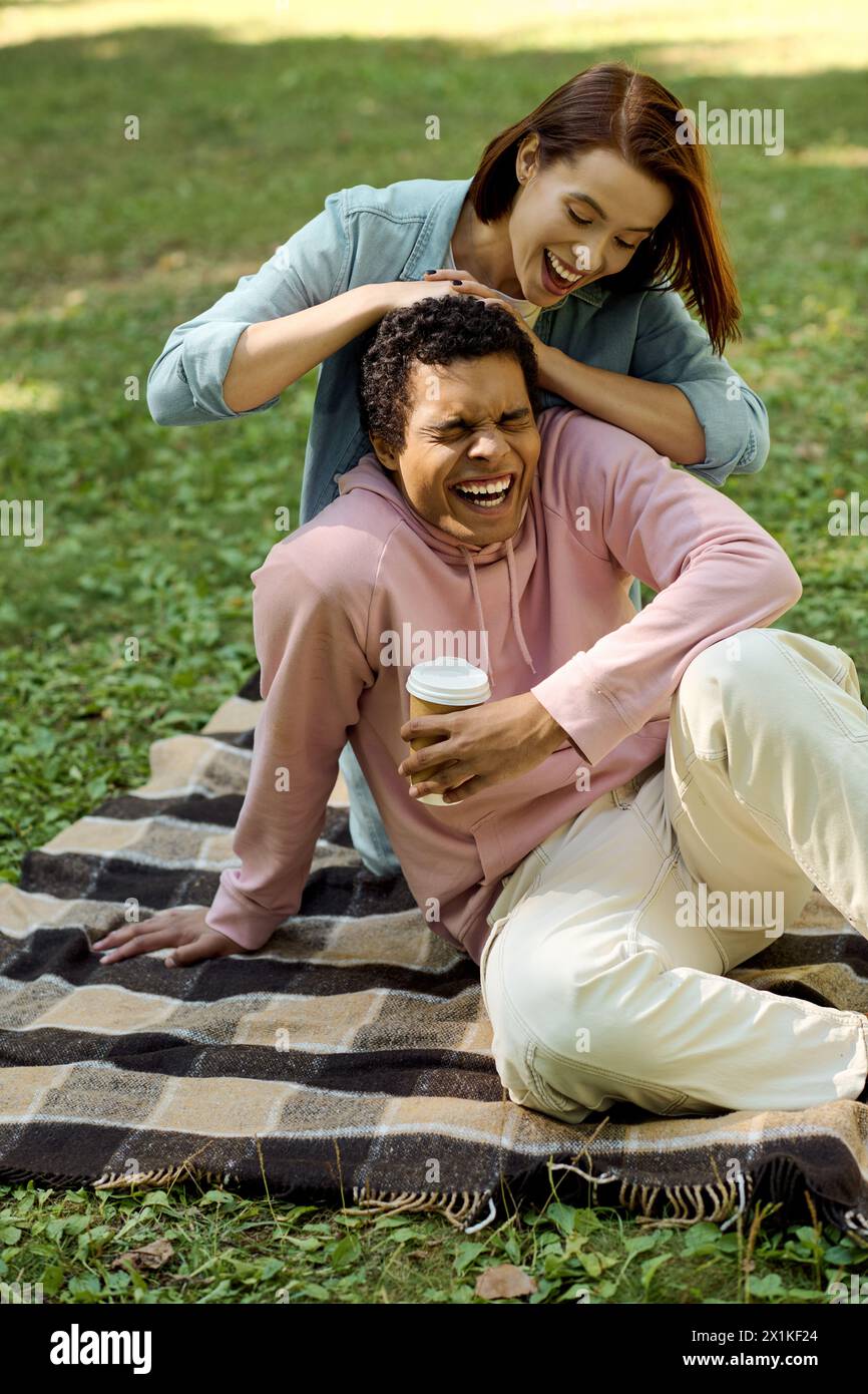 A diverse, loving couple sitting on a colorful blanket in a park ...