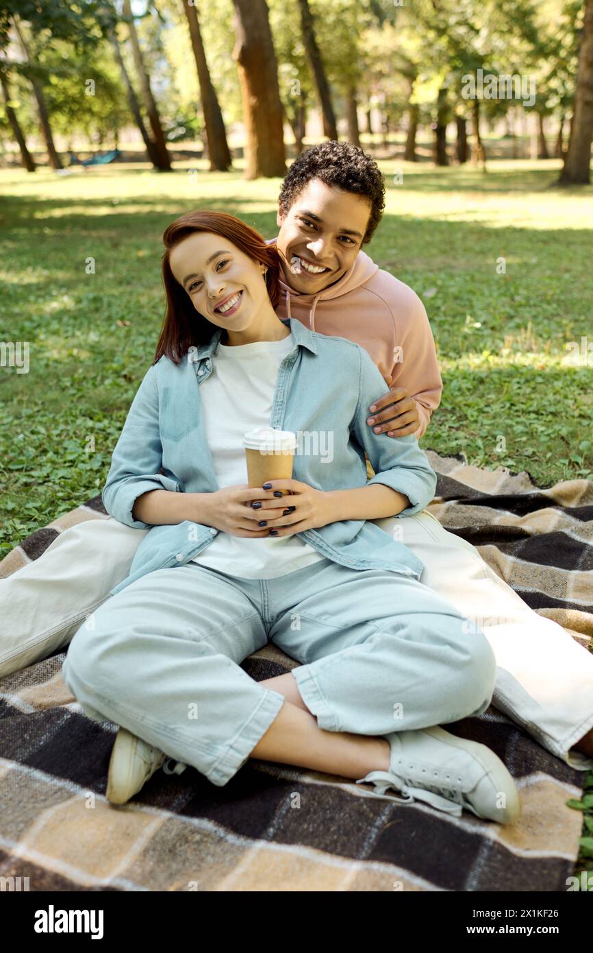 A diverse loving couple in vibrant attire sit on a blanket, sharing a ...