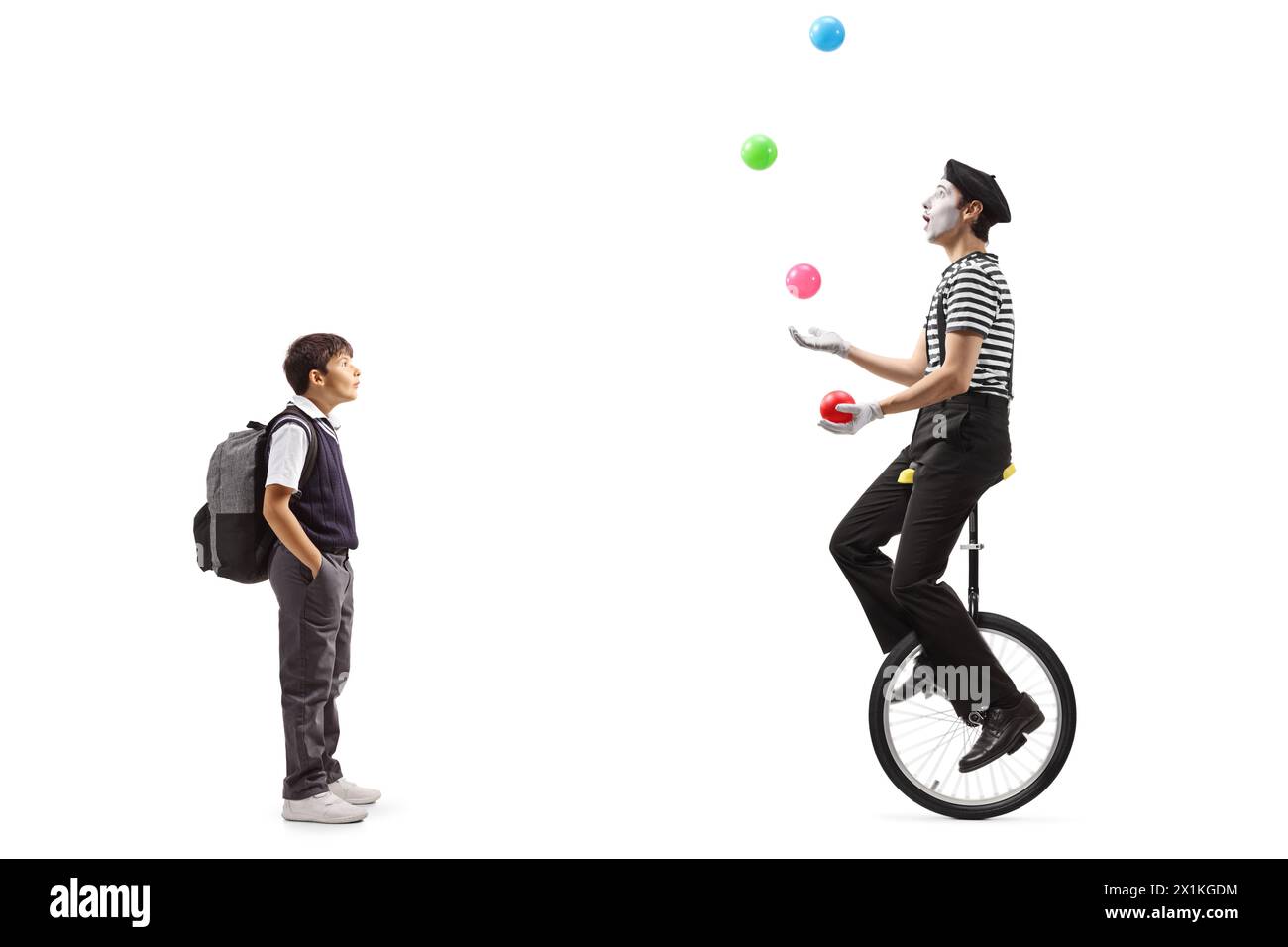 Full length shot of a schoolboy looking at a mime juggling with balls ...