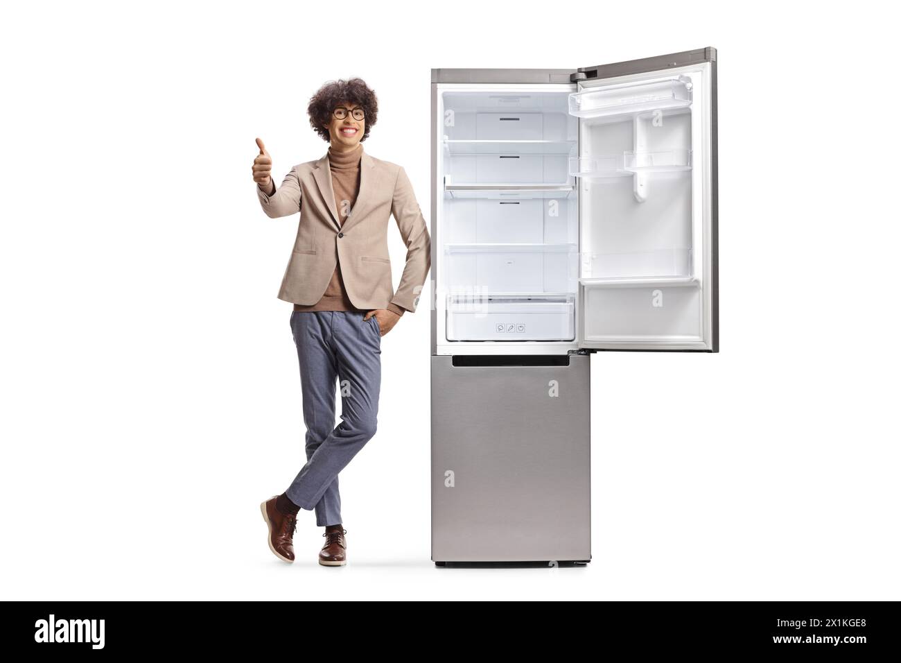 Young man gesturing thumbs up next to a new fridge isolated on white ...