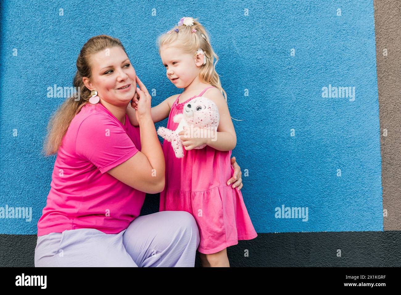 Mother holds and have fun her child with hearing aids and cochlear ...