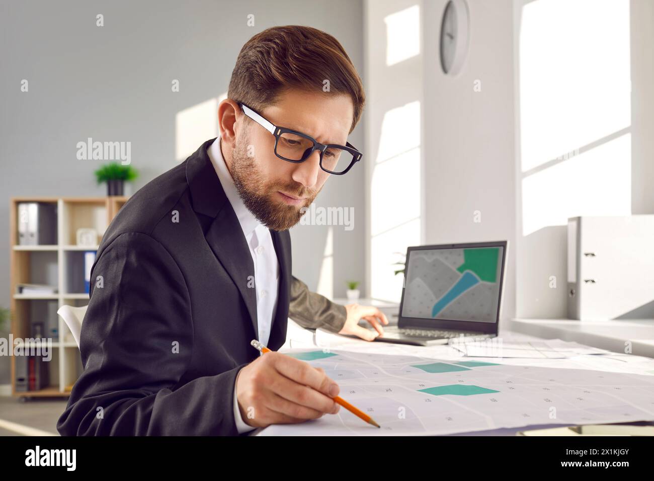 Cadastral surveyor sitting in office, working with cadastral maps and ...