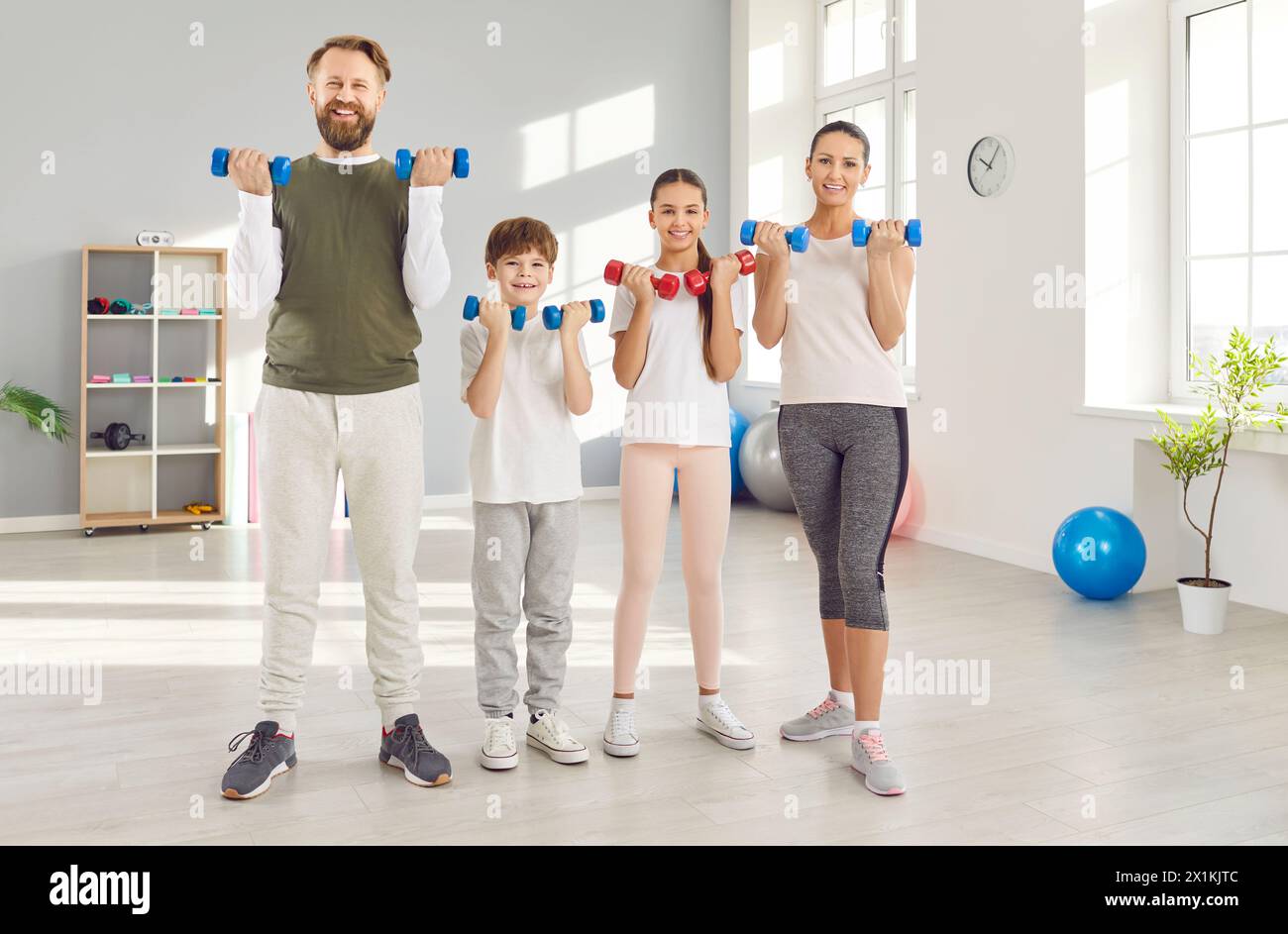 Cheerful active family with kids lifting dumbbells together in their ...