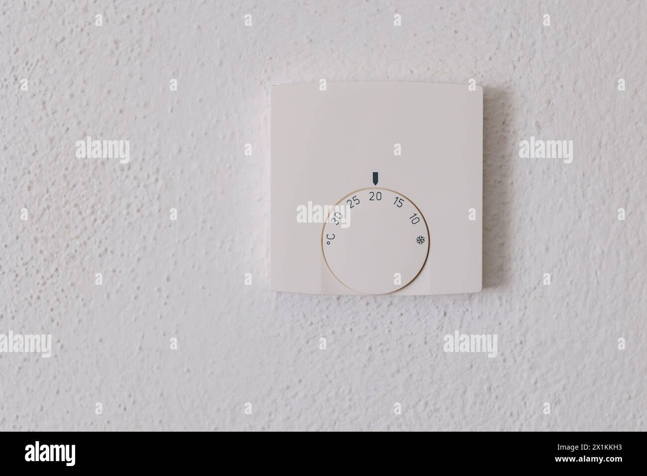 Room thermostat on the wall being adjusted. Temperature 20 degrees ...