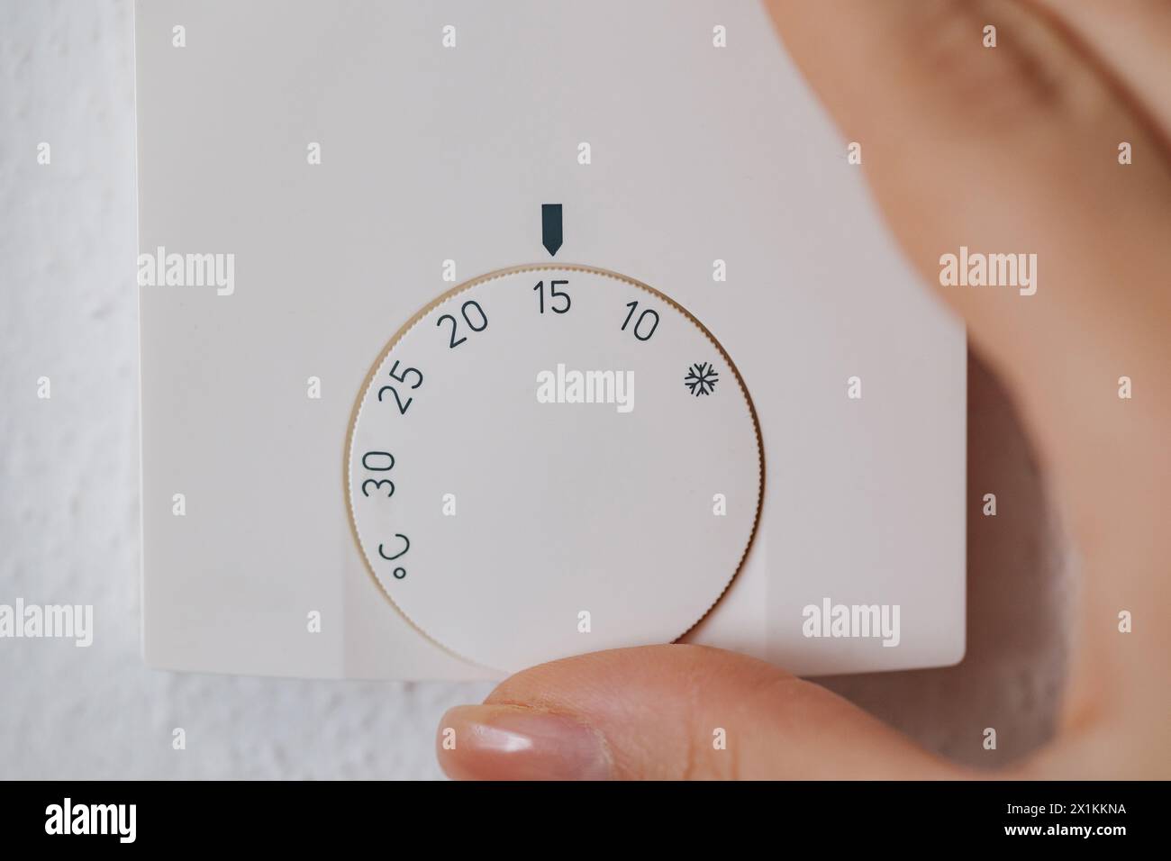 Female hand turns on central Heating thermostat, control dial ...