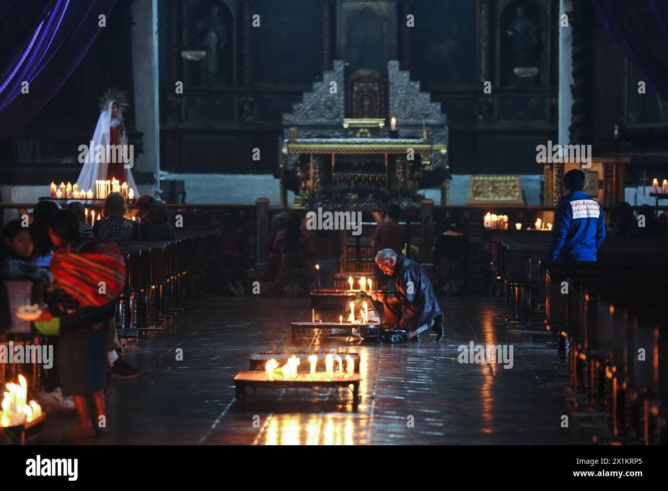 A Mayan indigenous man prays and burns candles on a altar platform ...
