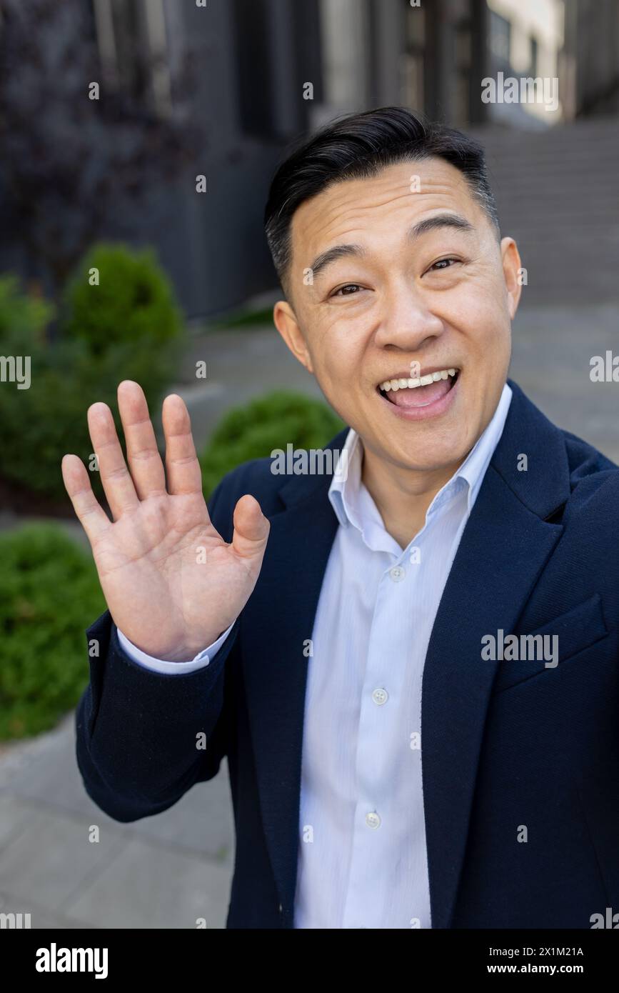 Vertical close-up photo of a young Asian businessman talking on a video ...