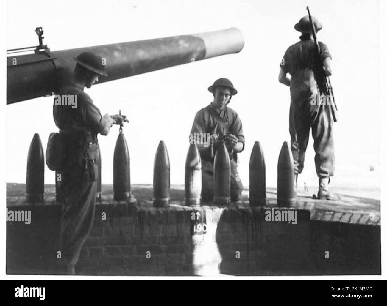 British Army personnel fuse shells under the barrel of coastal defense ...