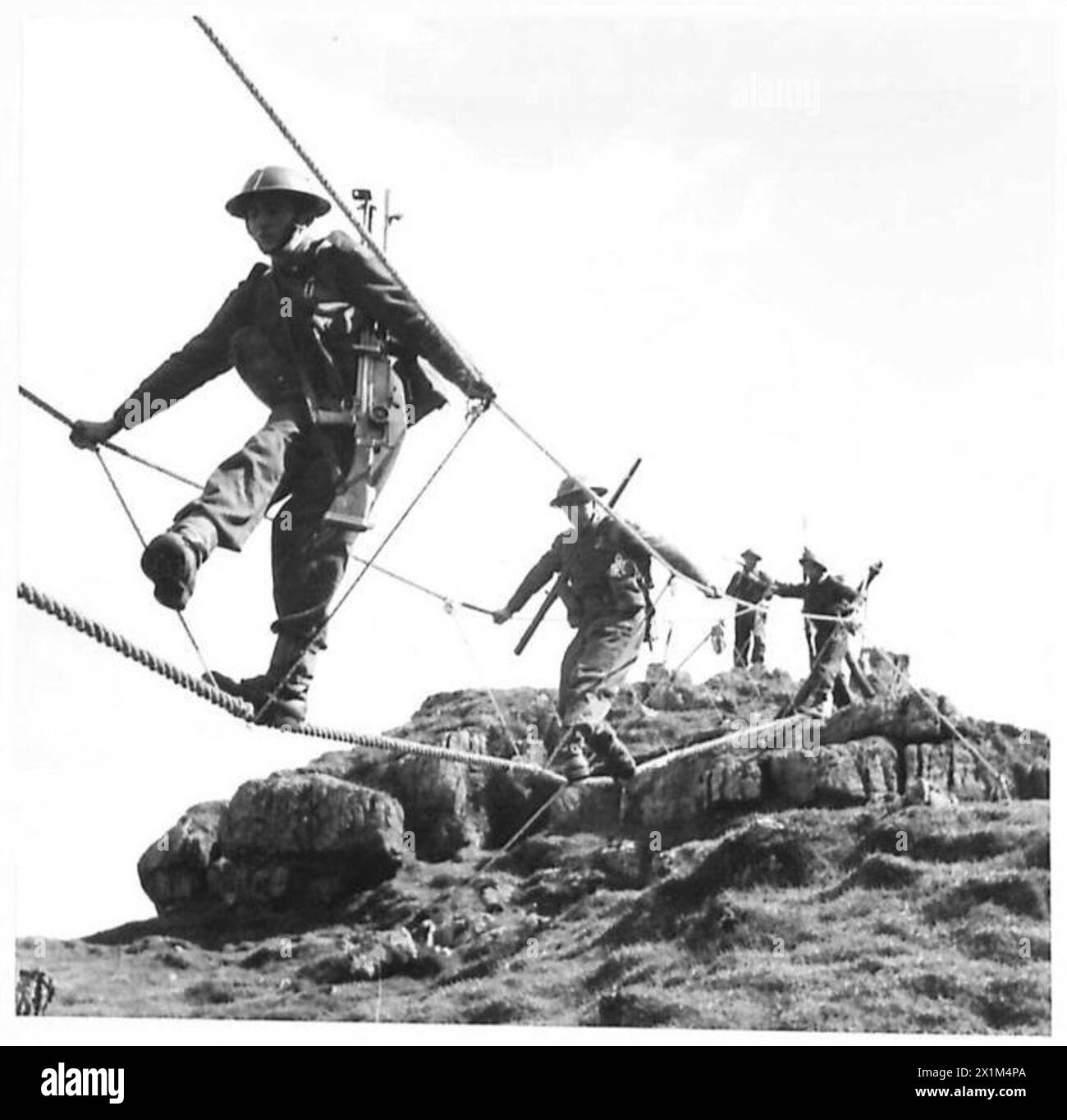 British Army personnel cross a ravine using a rope bridge as part of ...