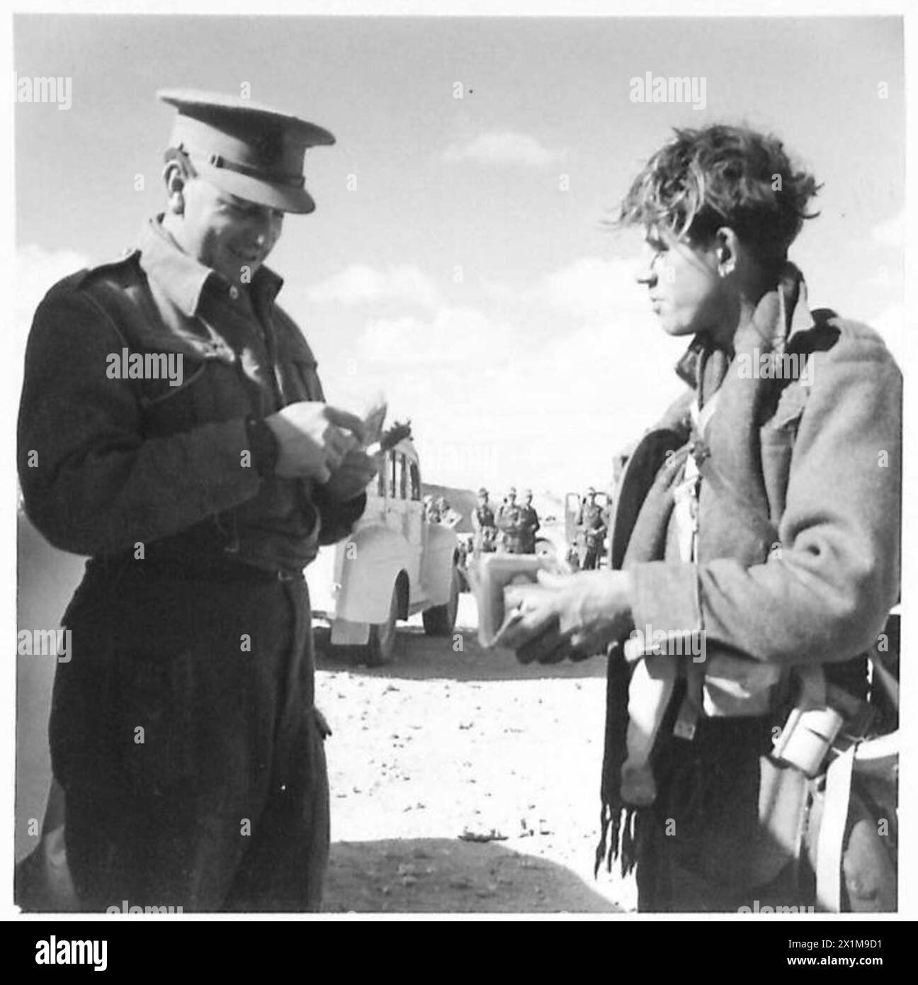 Infantrymen are depicted in a wartime photograph, advancing over a wire ...