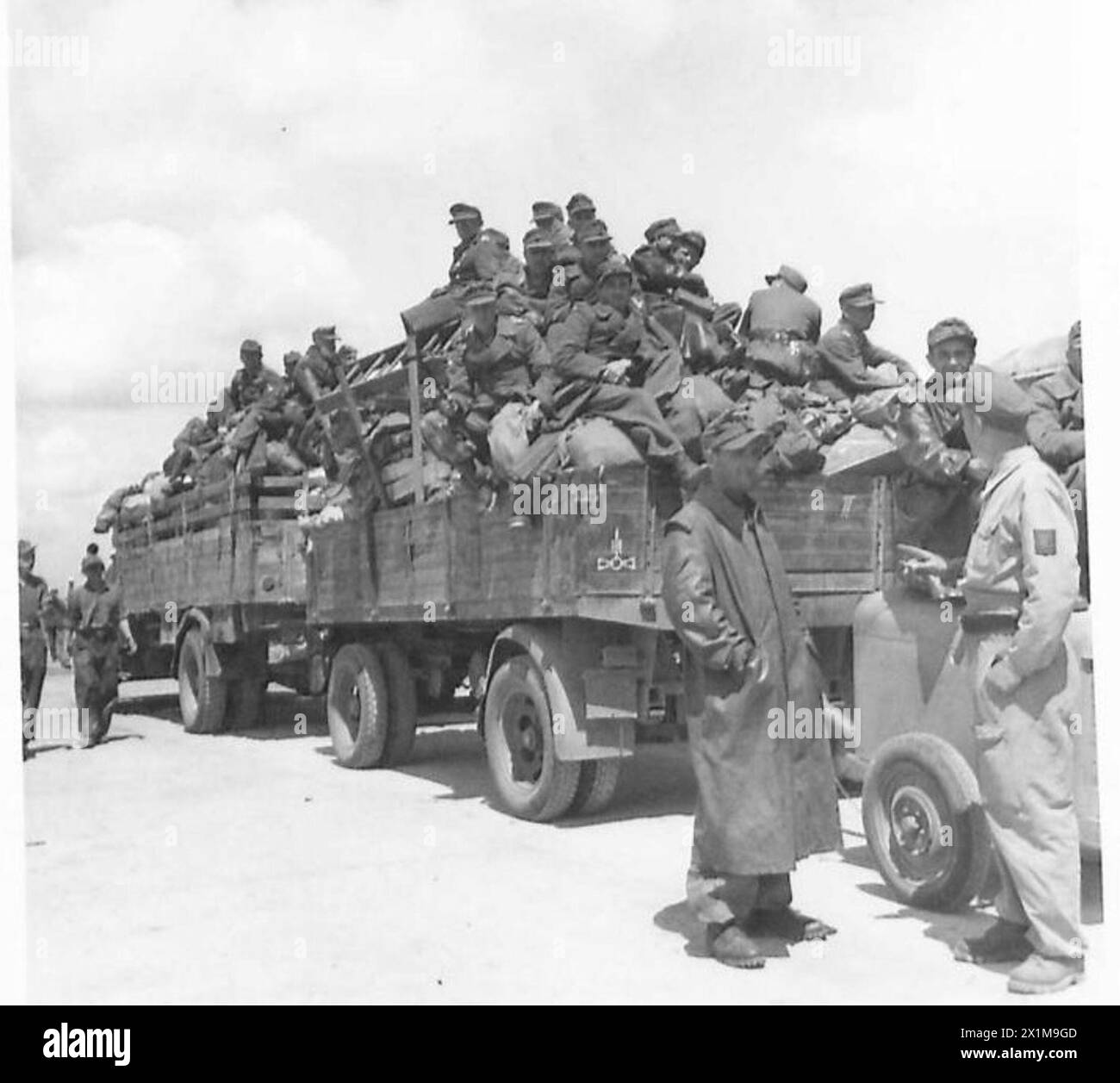 FIFTH ARMY PRISONER OF WAR CAMP - A convoy of German trucks, piled with ...