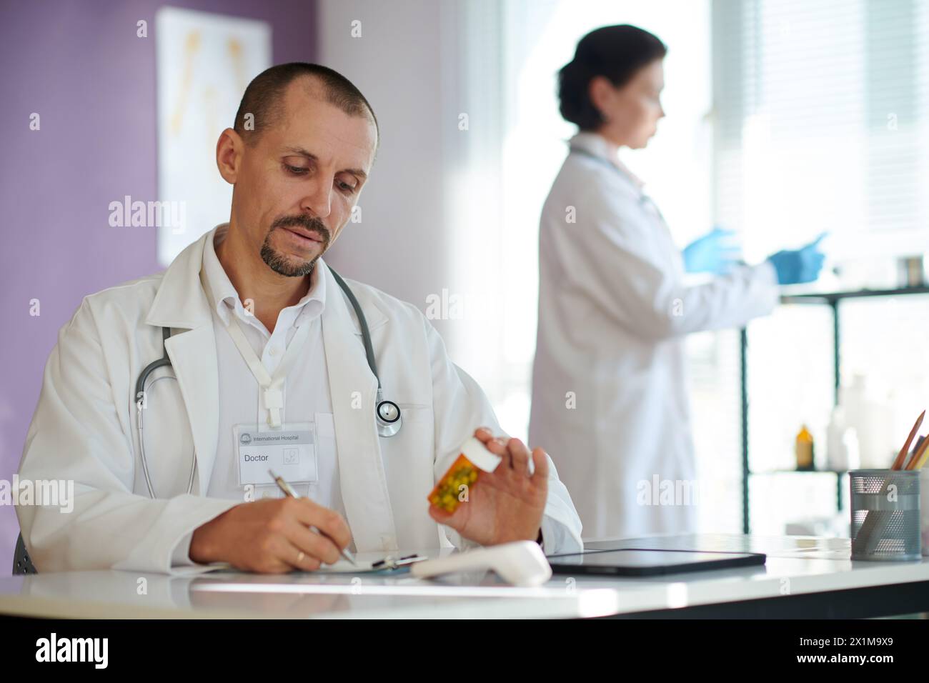 Portrait of doctor writing out prescription for patient Stock Photo - Alamy