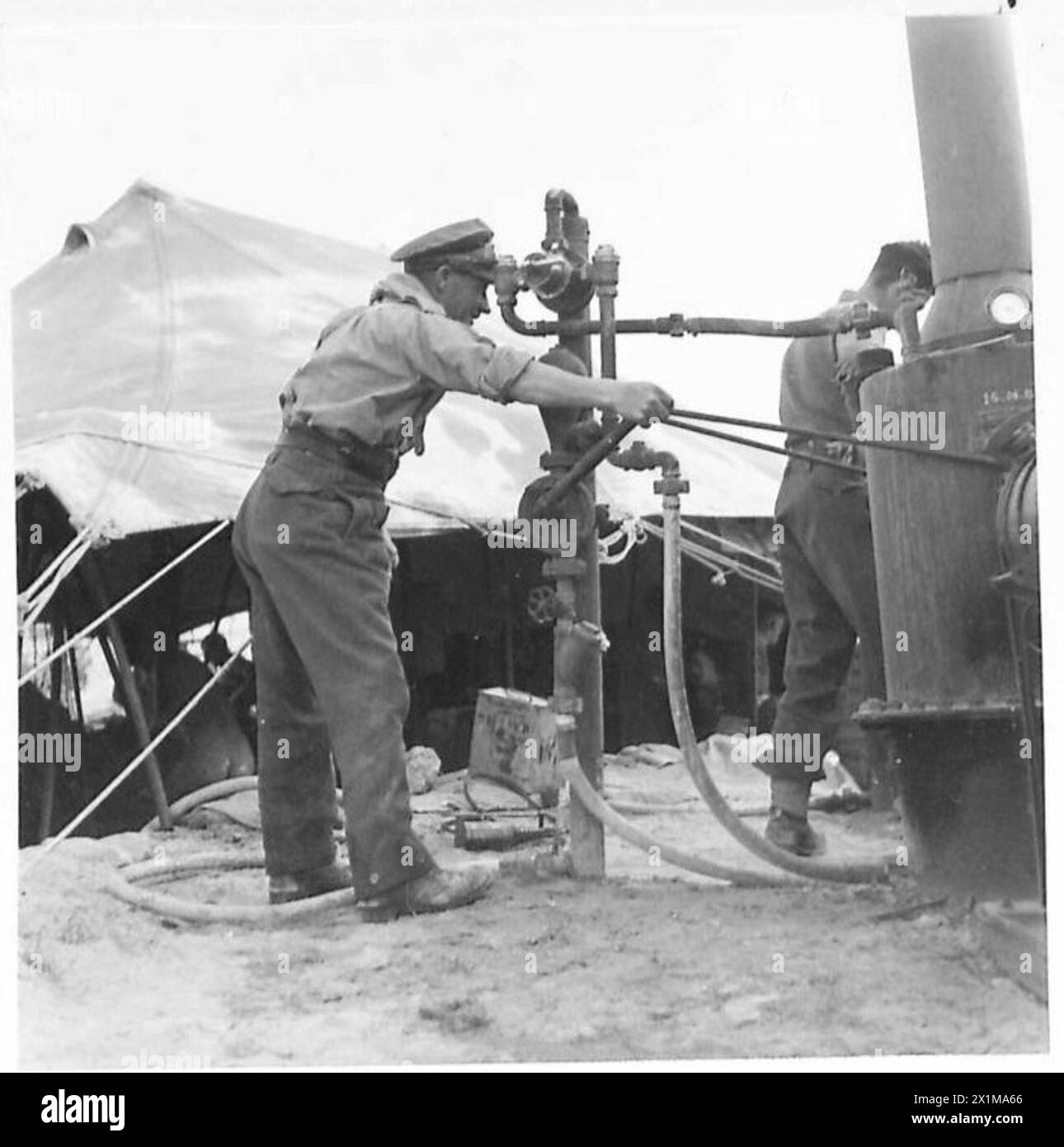 HOT BATHS FOR TROOPS IN THE WESTERN DESERT - Mobile Bath Unit staff pumping hot water into the ...