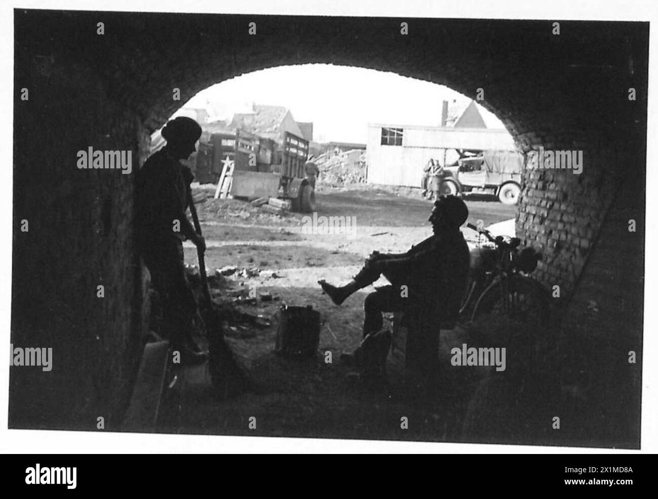Two British Army soldiers rest under the archway of a damaged windmill ...