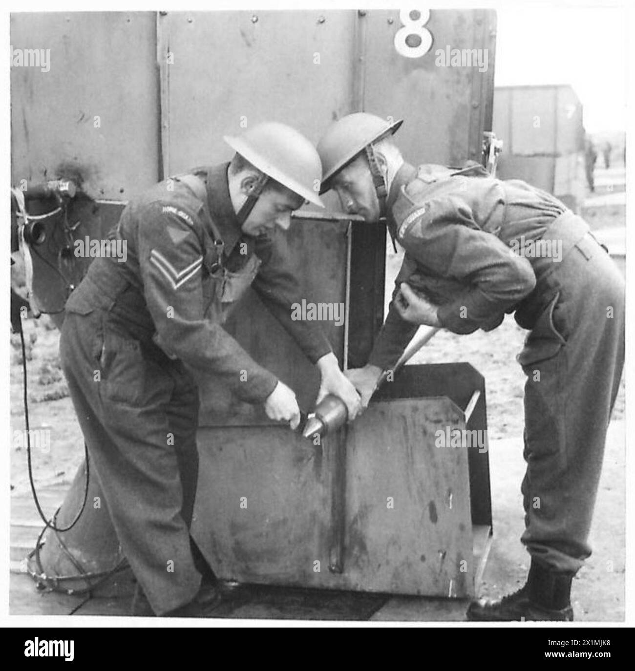 A Home Guard corporal sets the fuse on a rocket projector used with ...