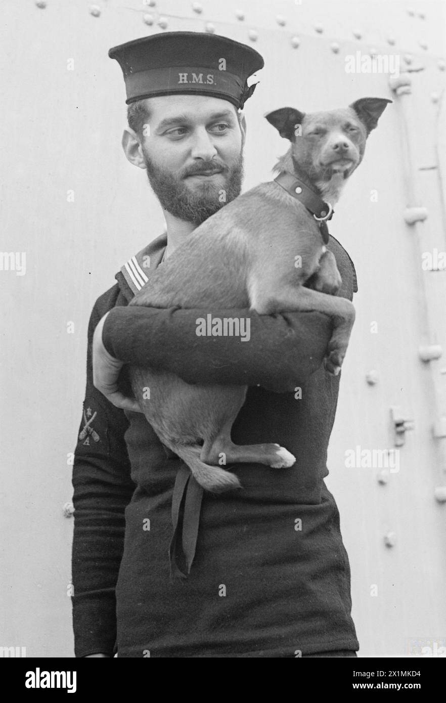 An Able Seaman aboard HMS Stork poses with the ship's mascot, Buster ...