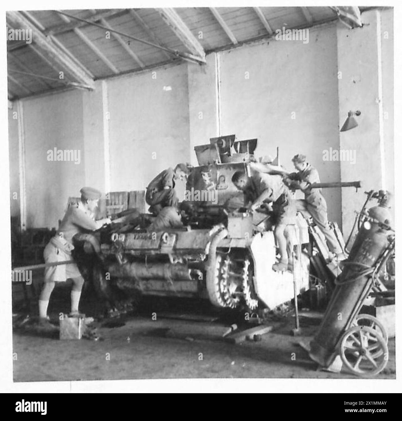 Mechanics work in a British Army tank repair shop in Tobruk, ensuring ...