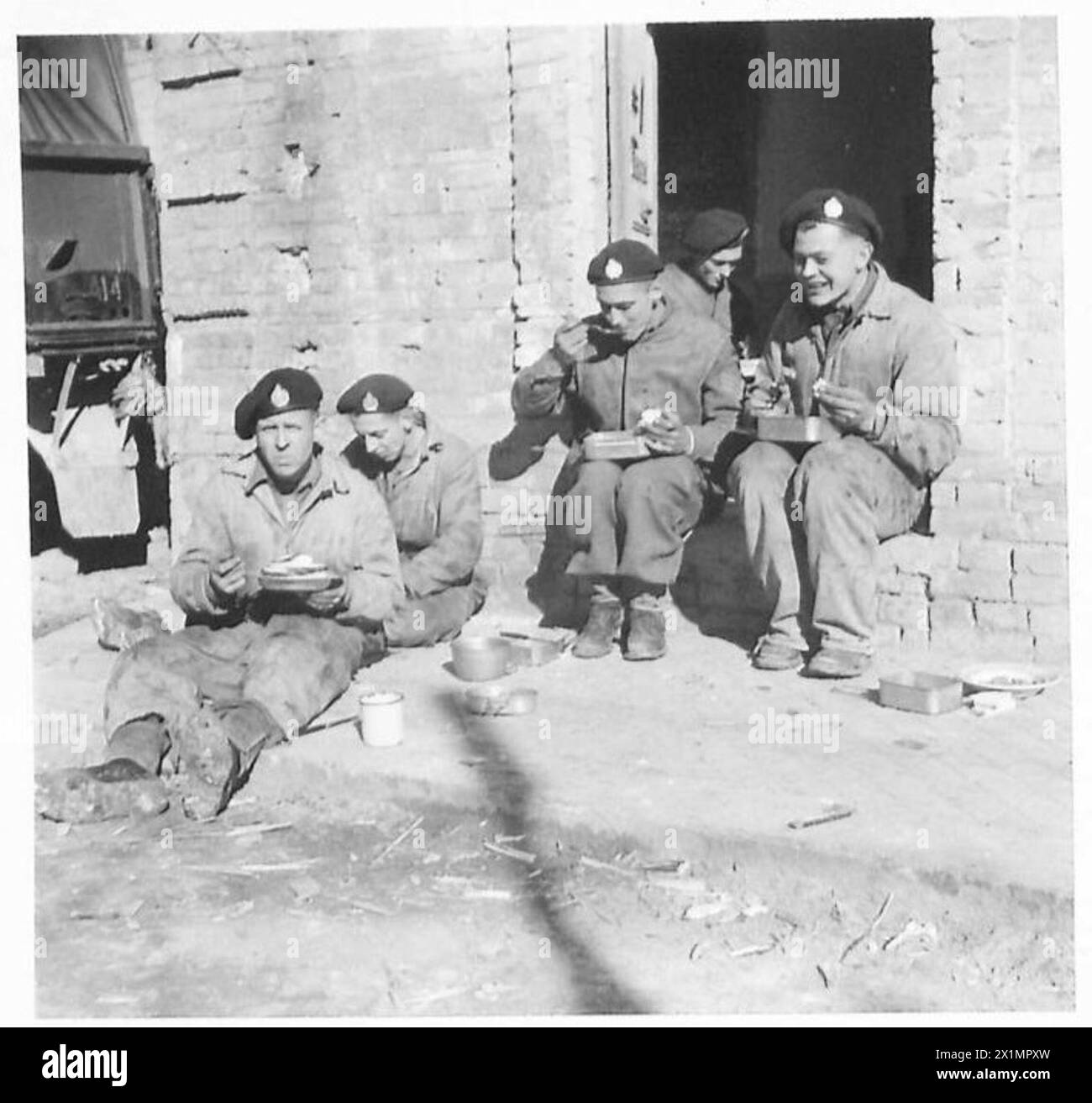 The crew of an Eighth Army tank eat their dinner outside their billet ...