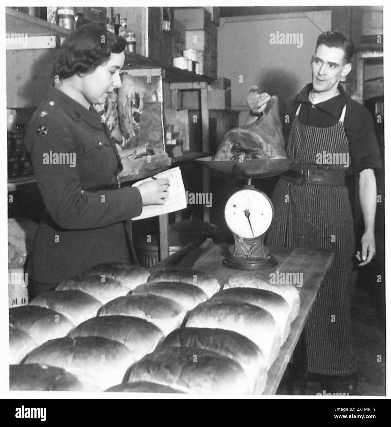 An ATS messing officer weighs bacon to ensure rations meet prescribed ...