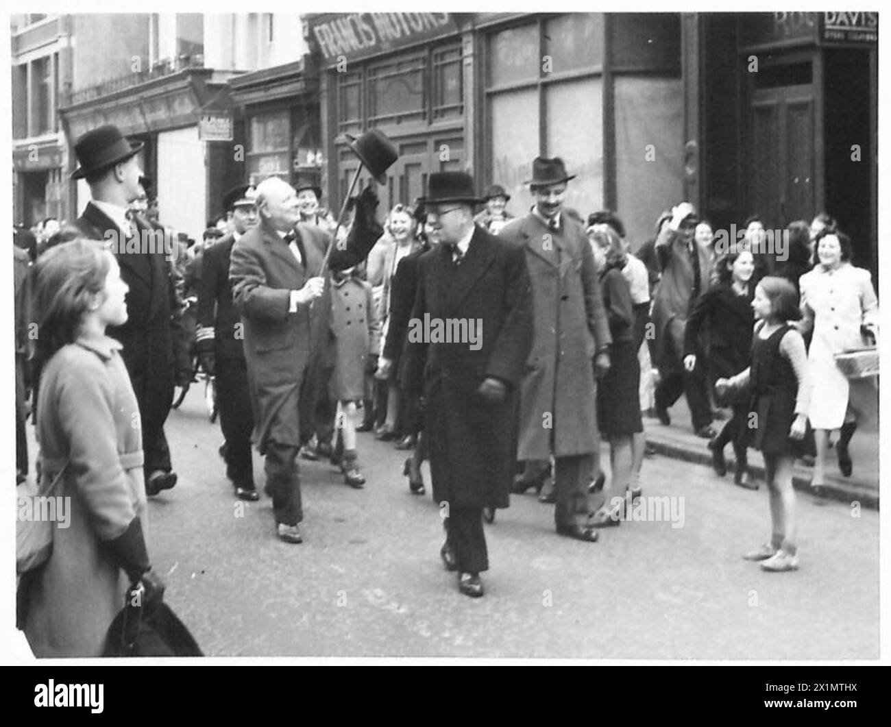 Winston Churchill raises his hat during a visit to Swansea, observed by ...