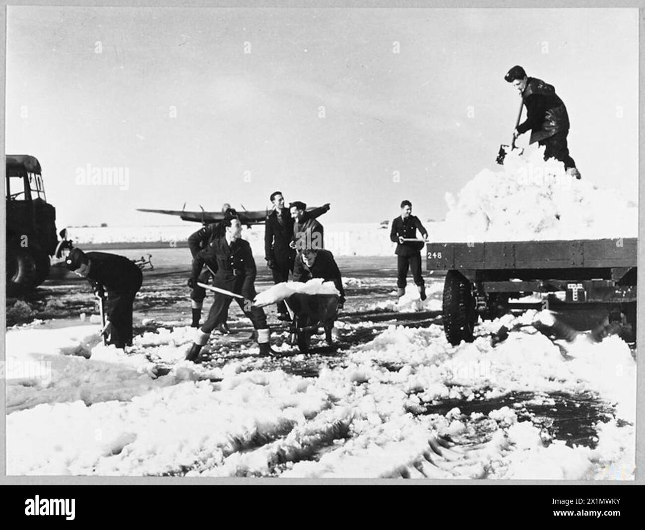 Ground crew at a RAF bomber station clear snow from a dispersal point ...