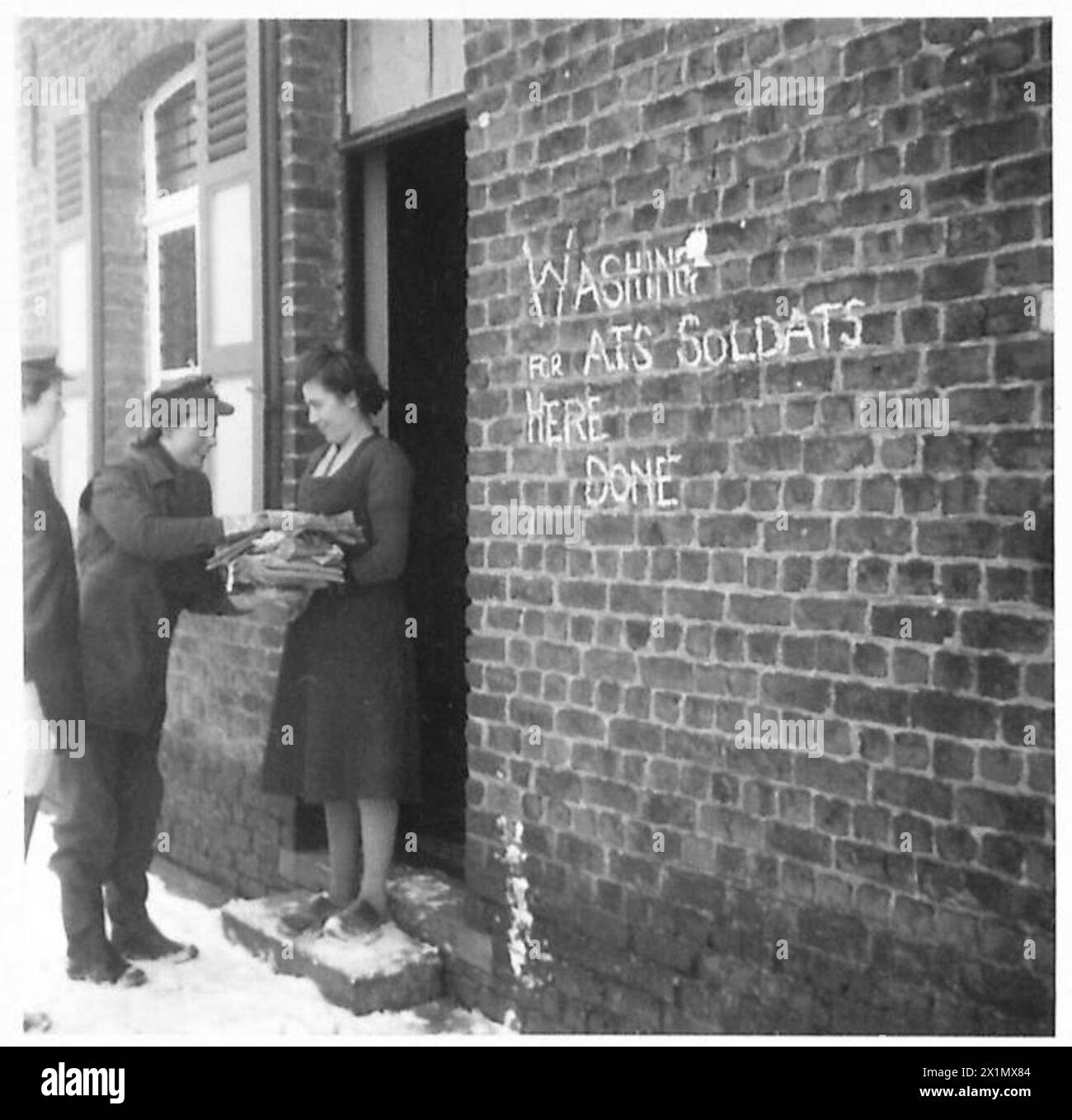An ATS member collects her laundry from a Belgian woman while serving ...