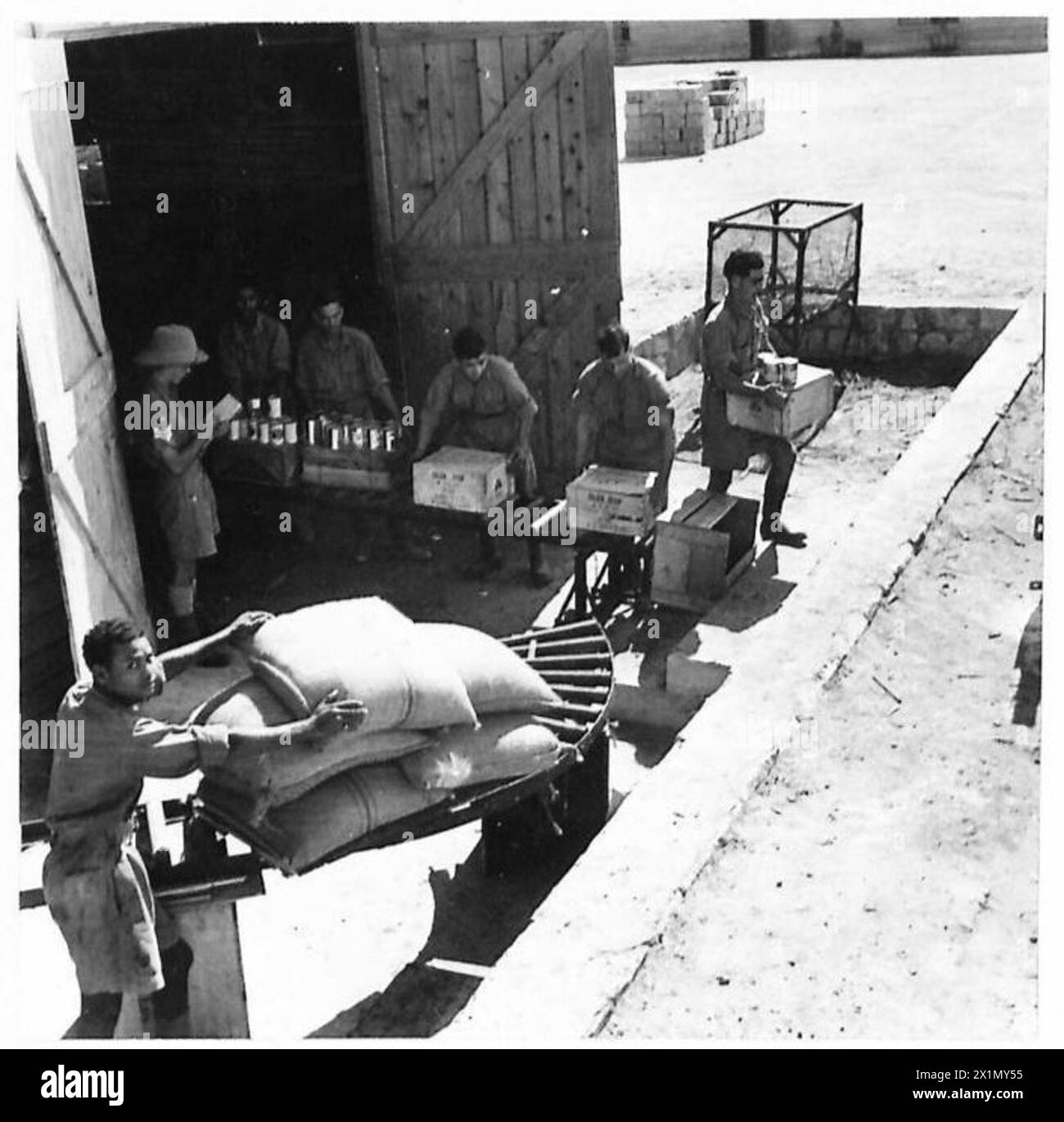 FEEDING THE TROOPS IN THE WESTERN DESERT - Food being conveyed from the storage shed on a roller ...