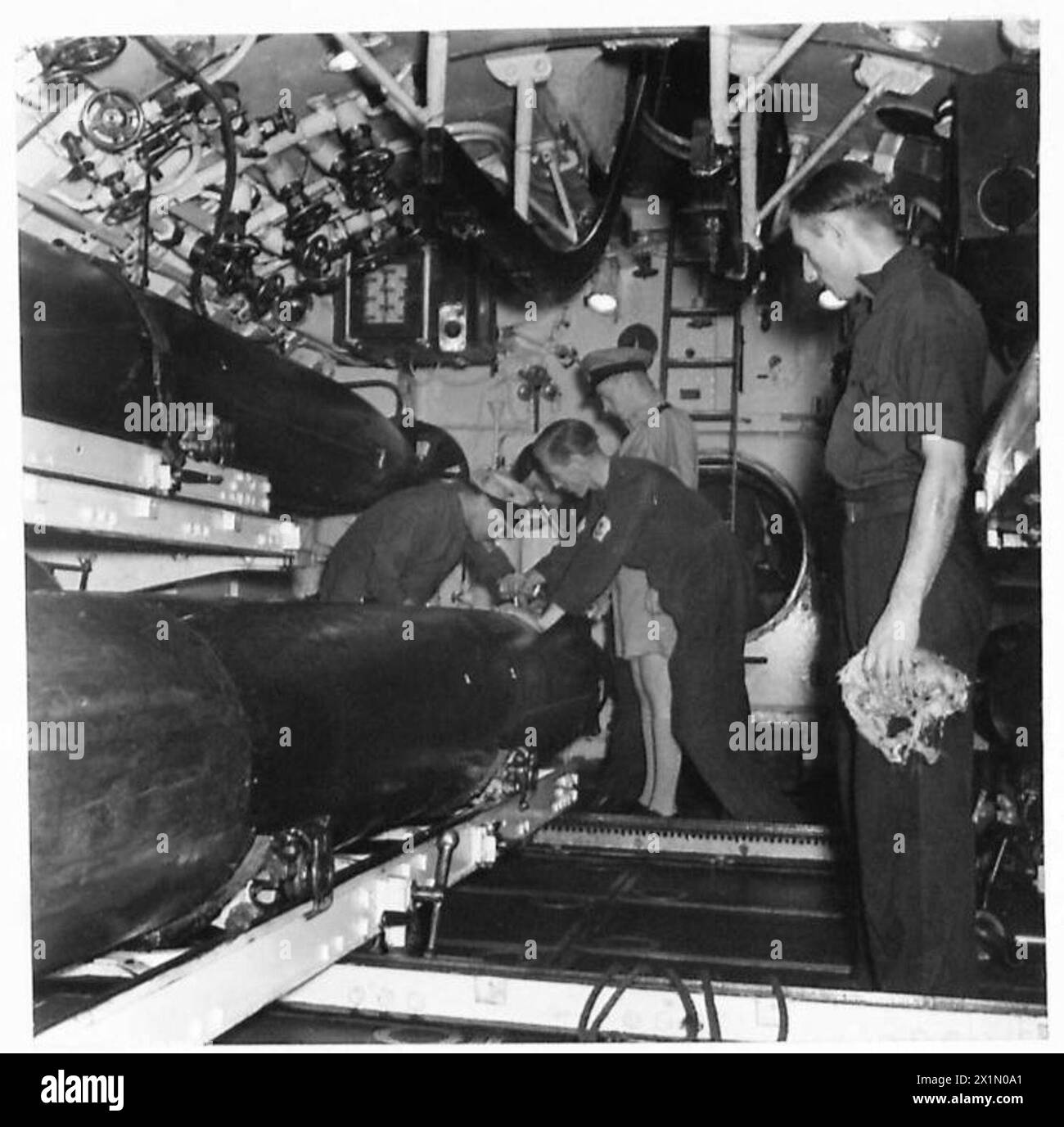 Fore end crew members performing adjustments on a torpedo aboard a ...