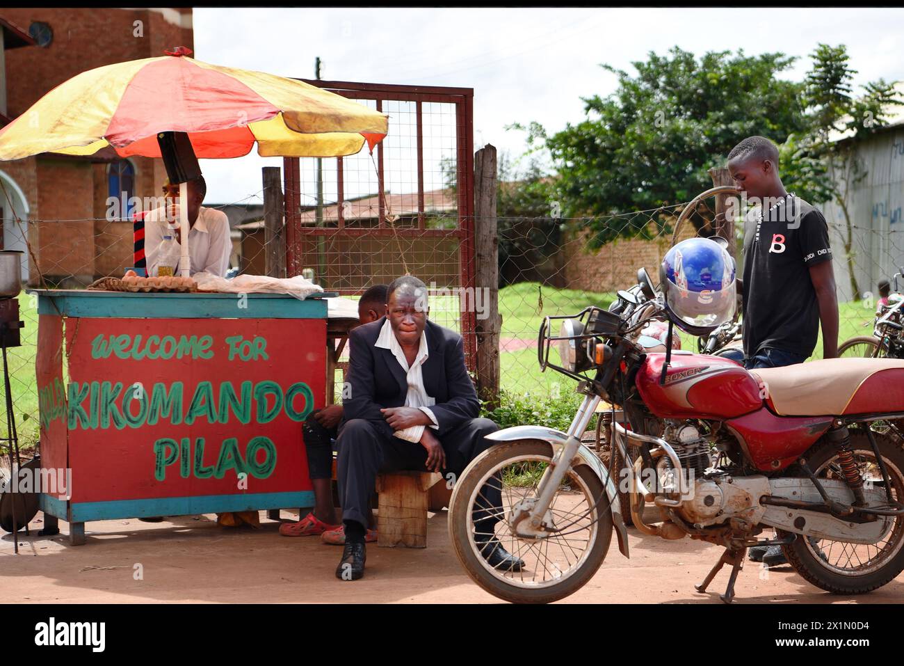 At the dusty roadside in Uganda, a man stands proudly by his egg stall ...