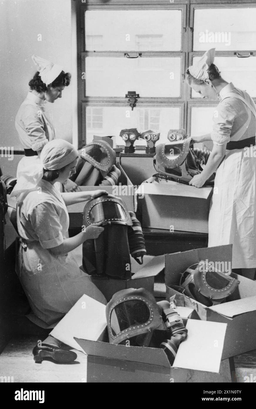At a London hospital in 1940, nurses test and prepare gas masks for ...