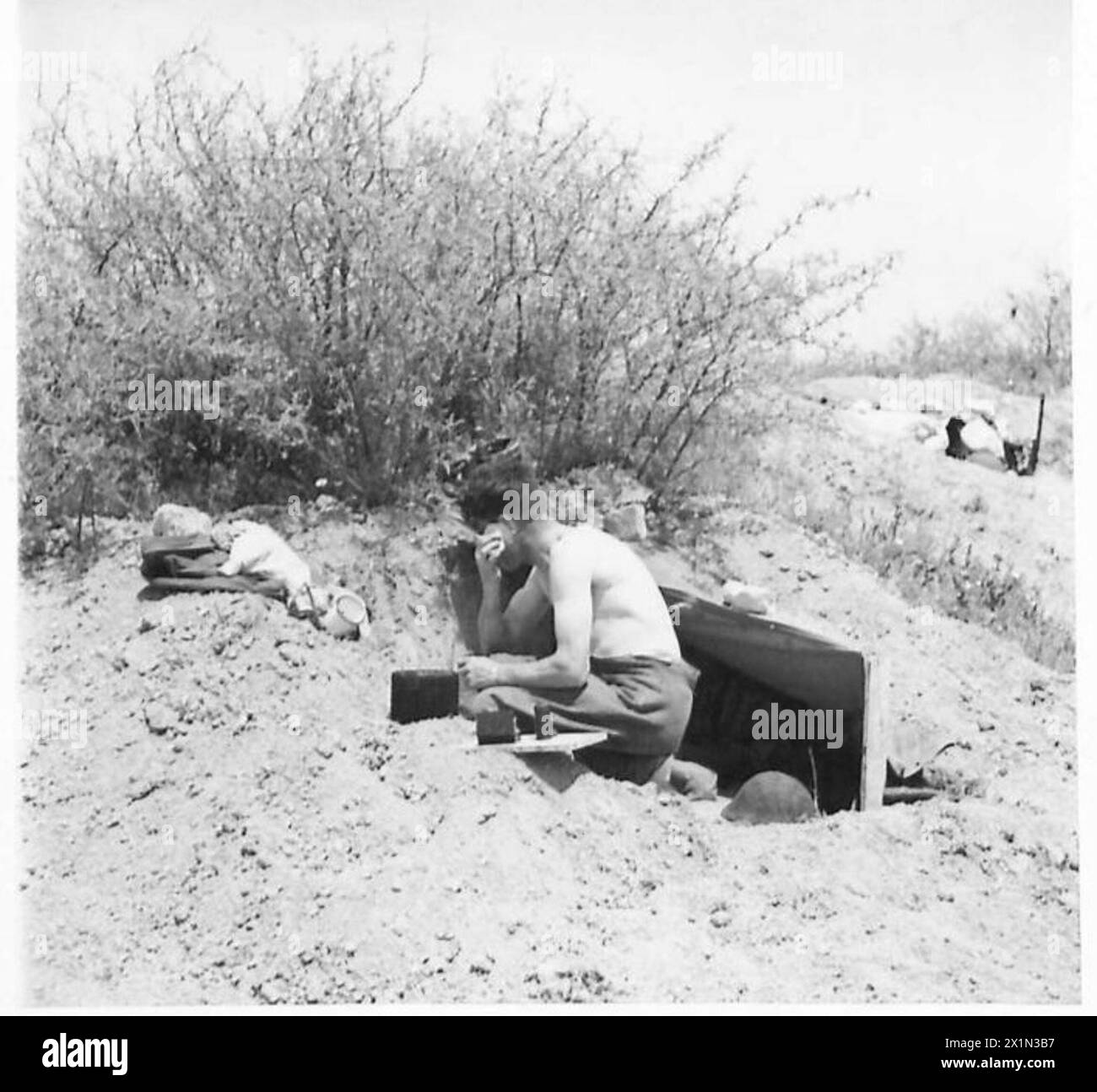 A Guardsman in a dugout performs his morning routine in the field ...