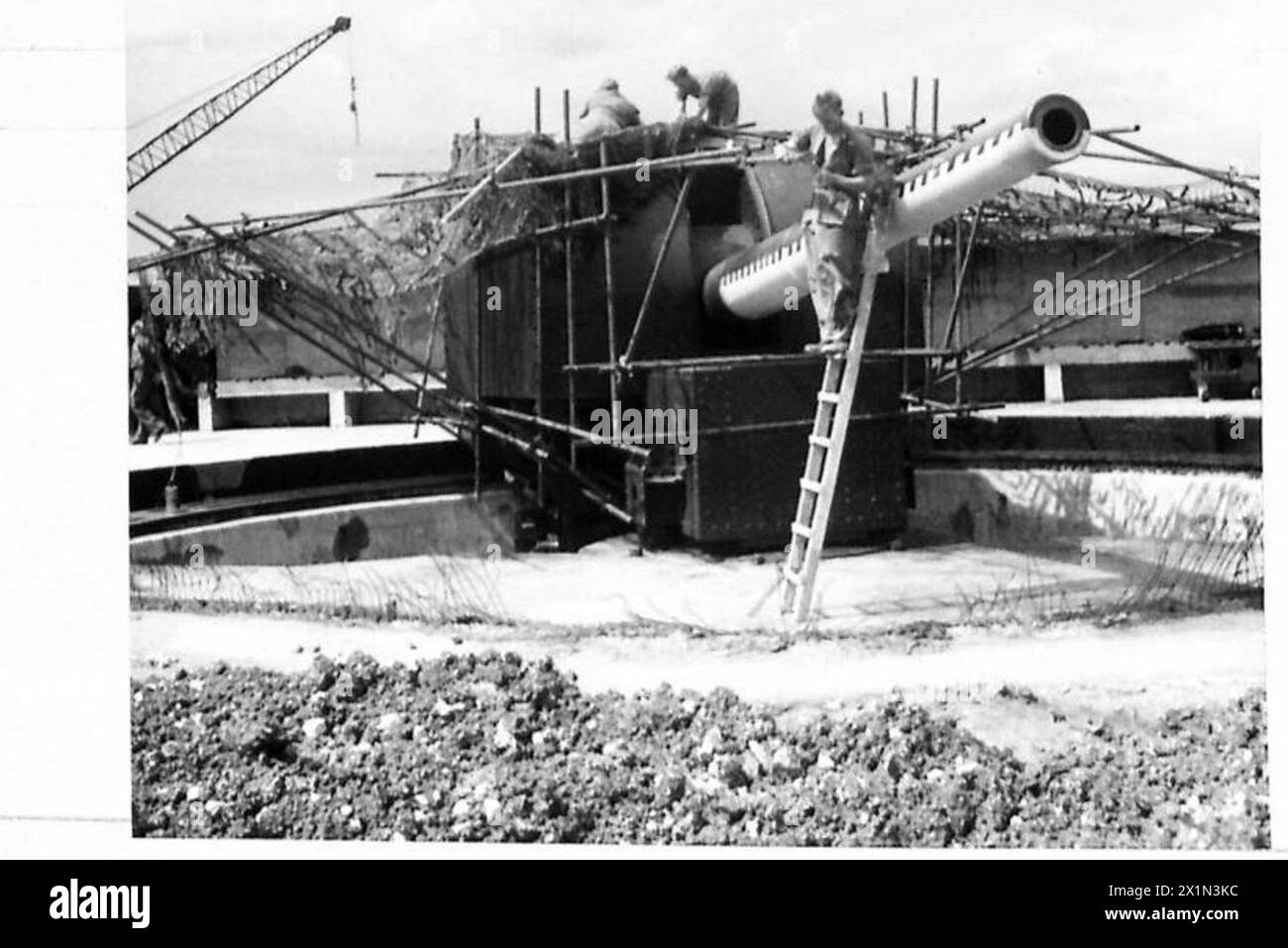 Scaffolding and camouflage netting are erected to conceal coastal guns ...