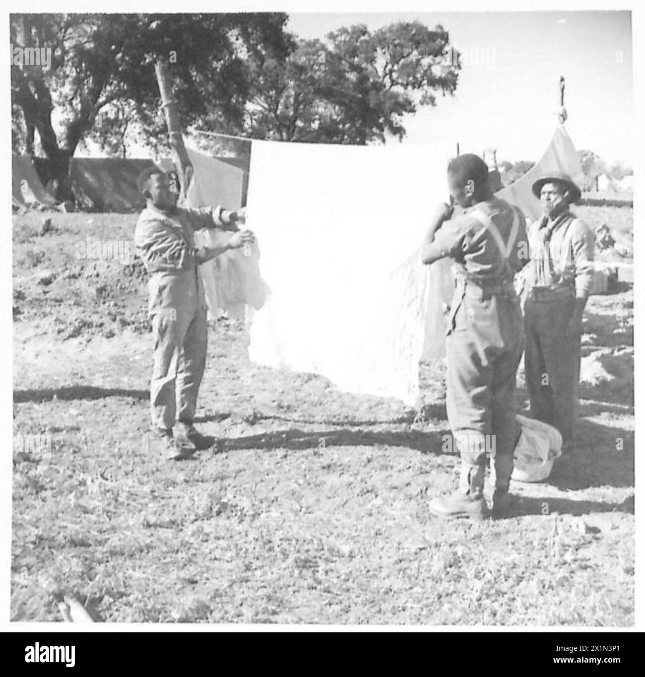 Basuto Pioneer Corps men assist in hanging laundry while nurses operate ...
