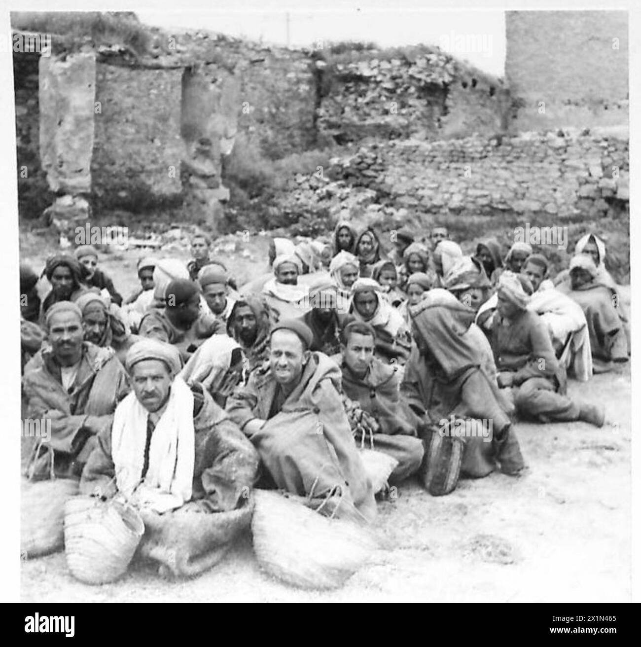 Arabs in North Africa wait outside a market to purchase goods, with the ...