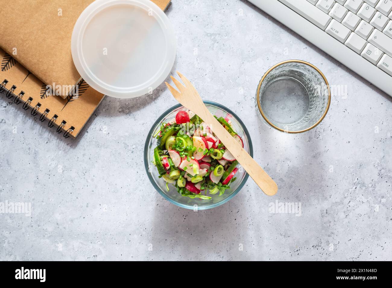 Healthy food in a office. Prepared radish and cucumber salad on a desk ...