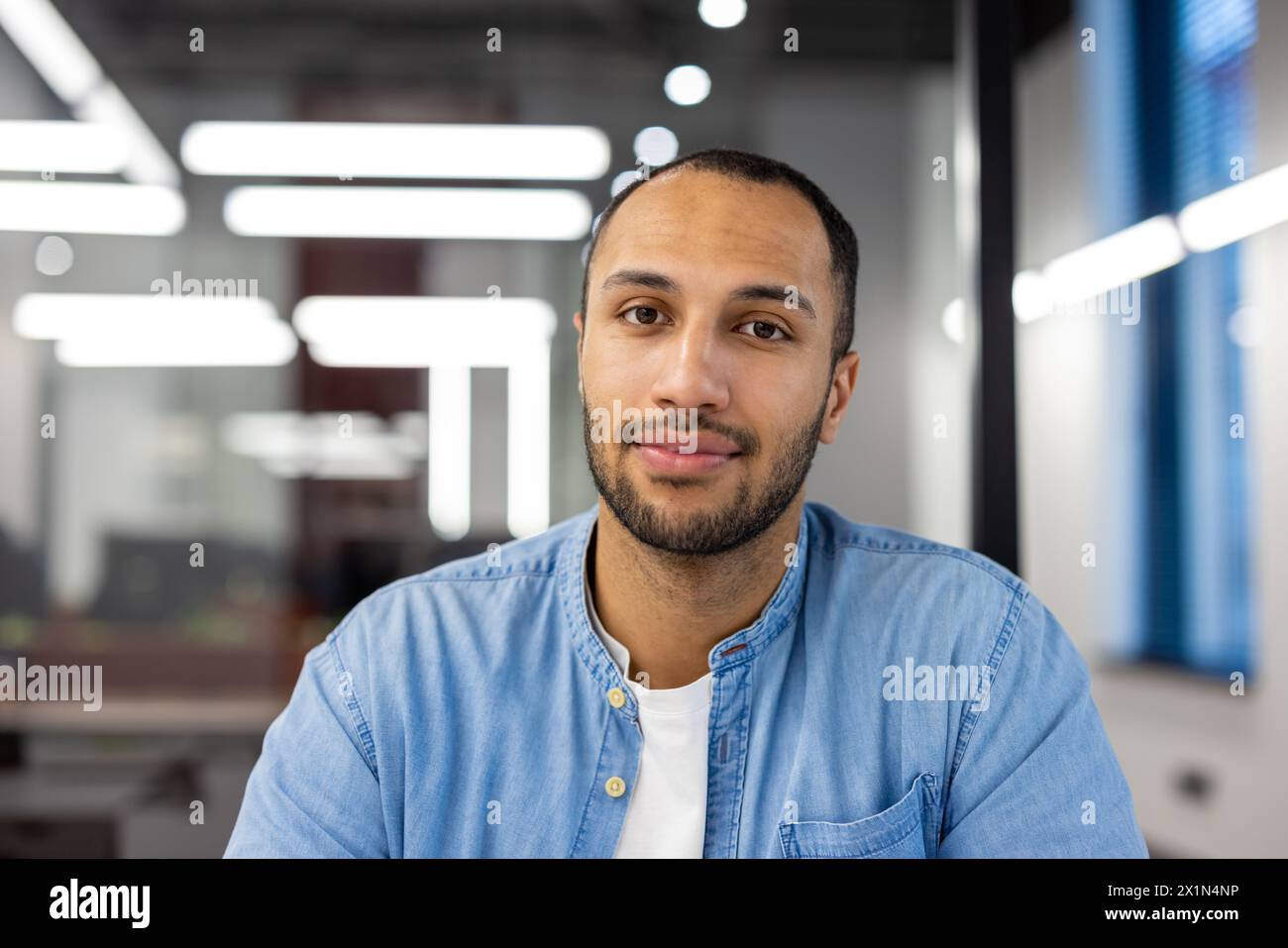 Close-up portrait of a young Muslim man sitting in a modern office in a ...