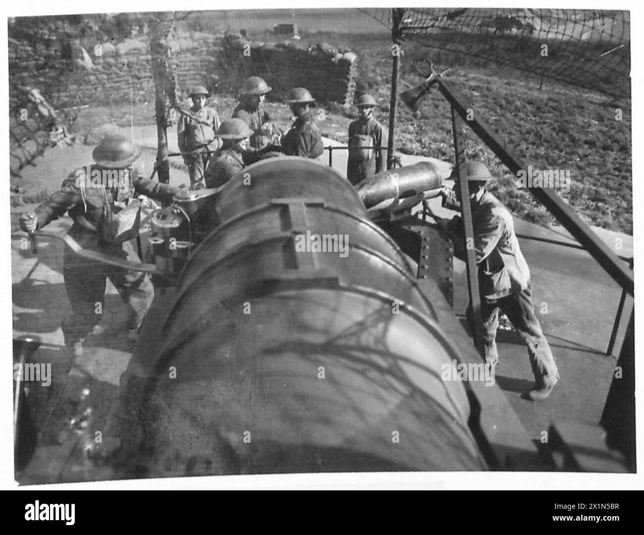 A gun crew at action stations is loading a shell into the artillery ...
