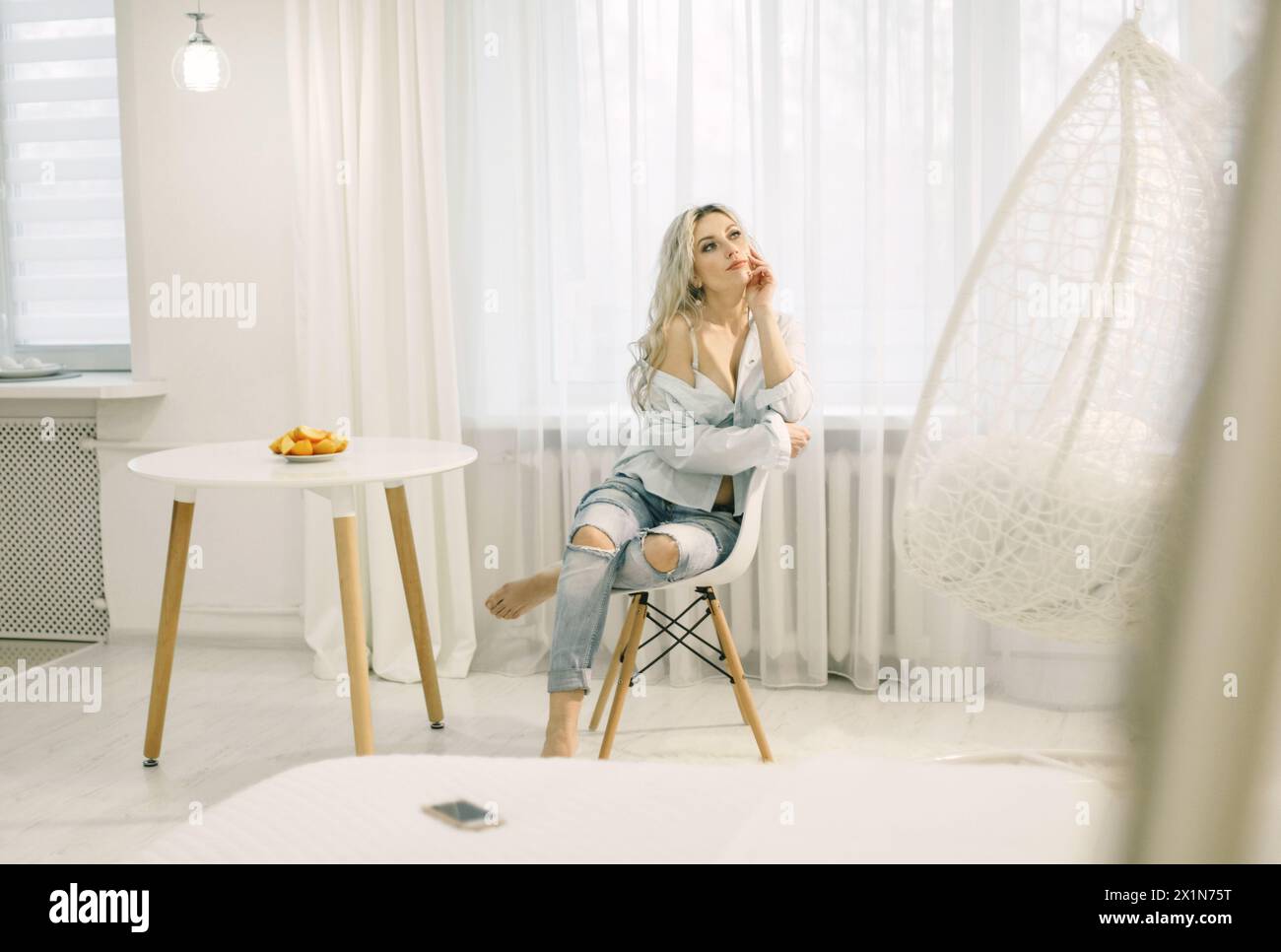 A woman is seated in a chair, facing a window. She gazes outside ...