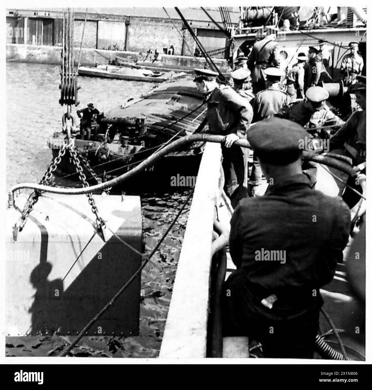 A diving bell is lowered over a ship's side by Royal Engineers ...