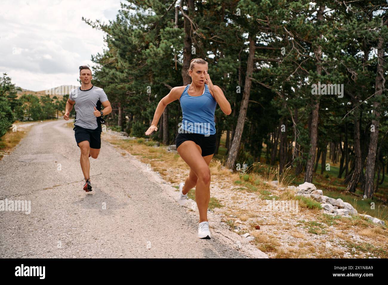 A couple dressed in sportswear runs along a scenic road during an early ...