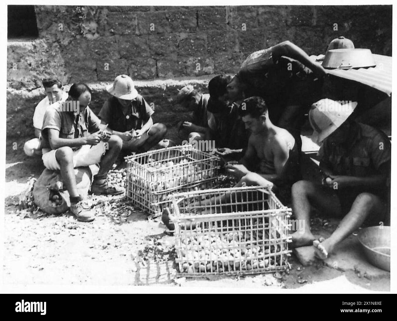 A squad performs cookhouse duties, peeling potatoes for dinner in a ...