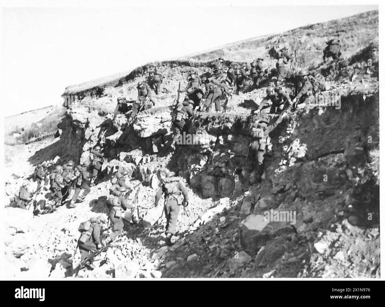 Suffolk Regiment soldiers train by scrambling up a rocky hillside ...
