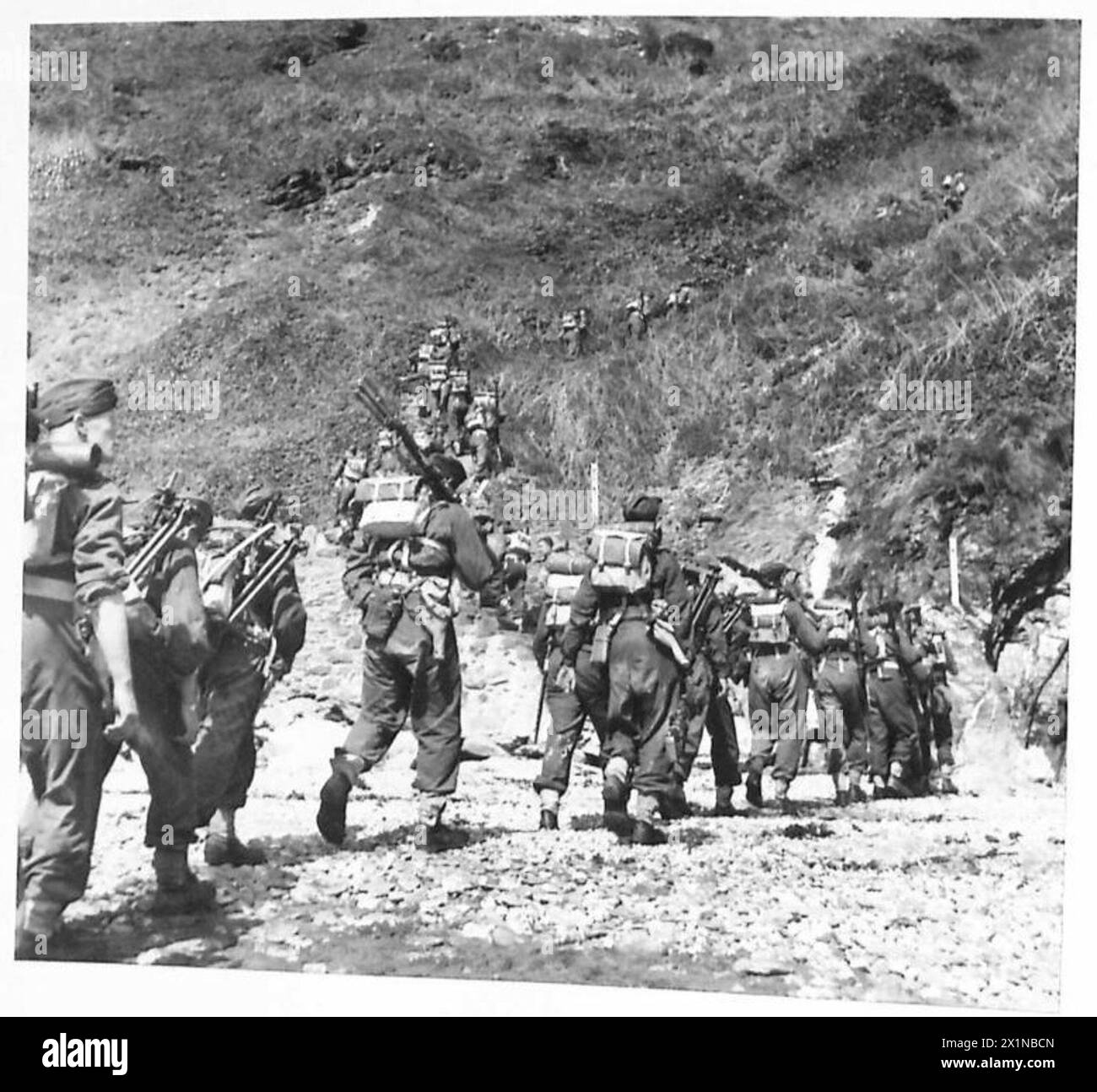 LIVING ON THE COUNTRY - Men climbing a steep hillside and carrying full ...