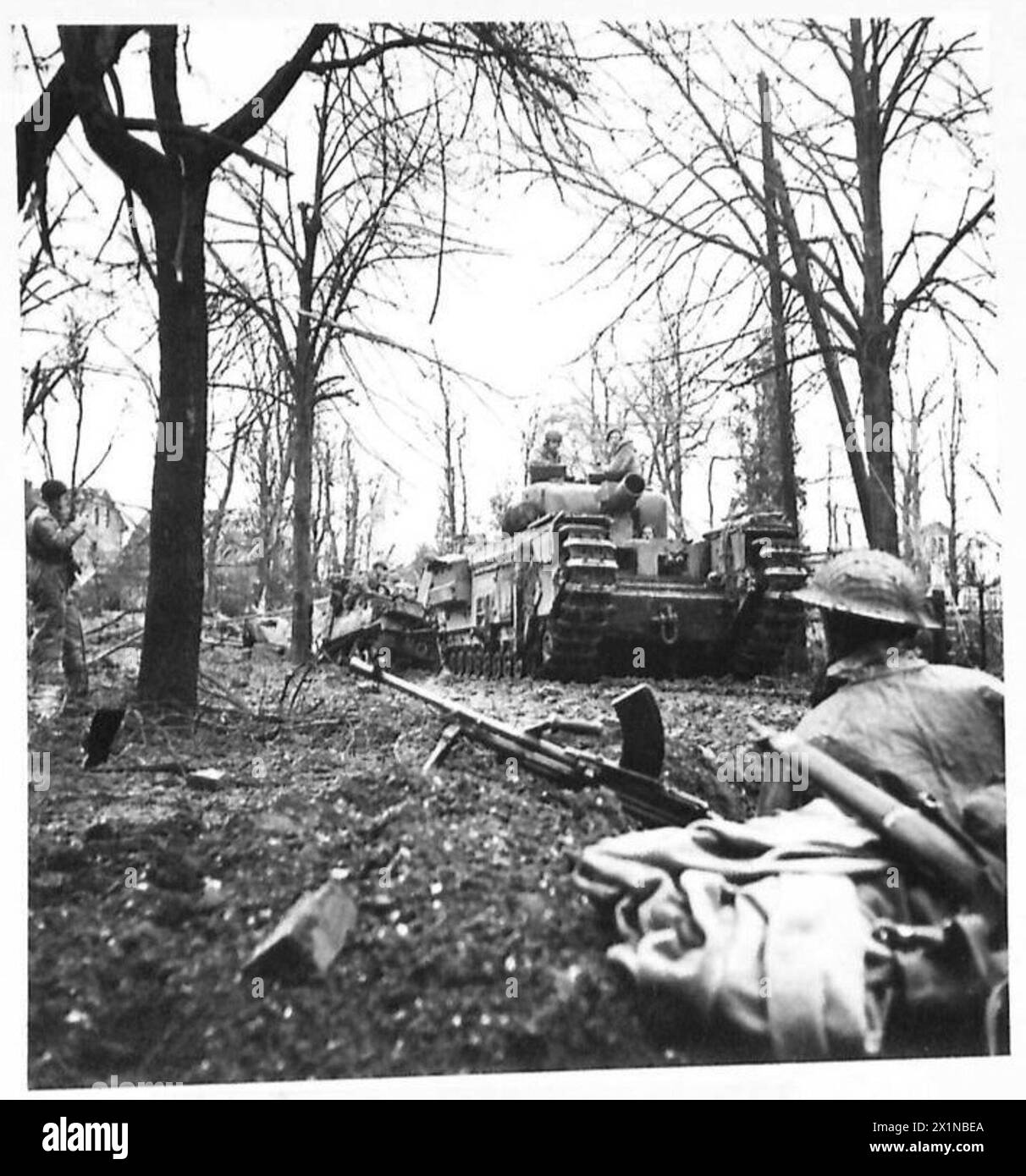 BRITISH TROOPS IN KLEVE - A Bren carrier being towed across the rubble ...