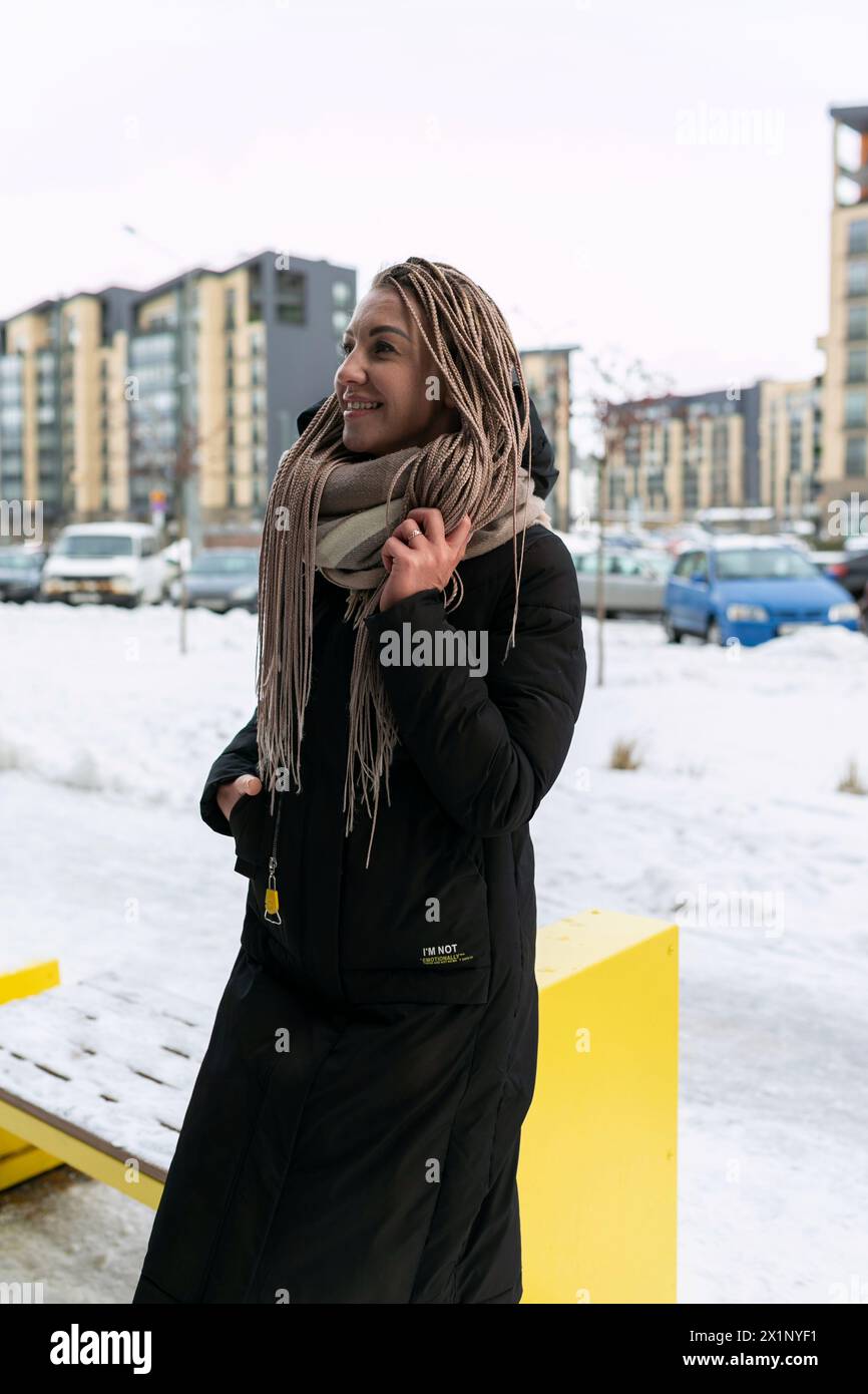 A pretty young woman with blond dreadlocks walks through the city in ...