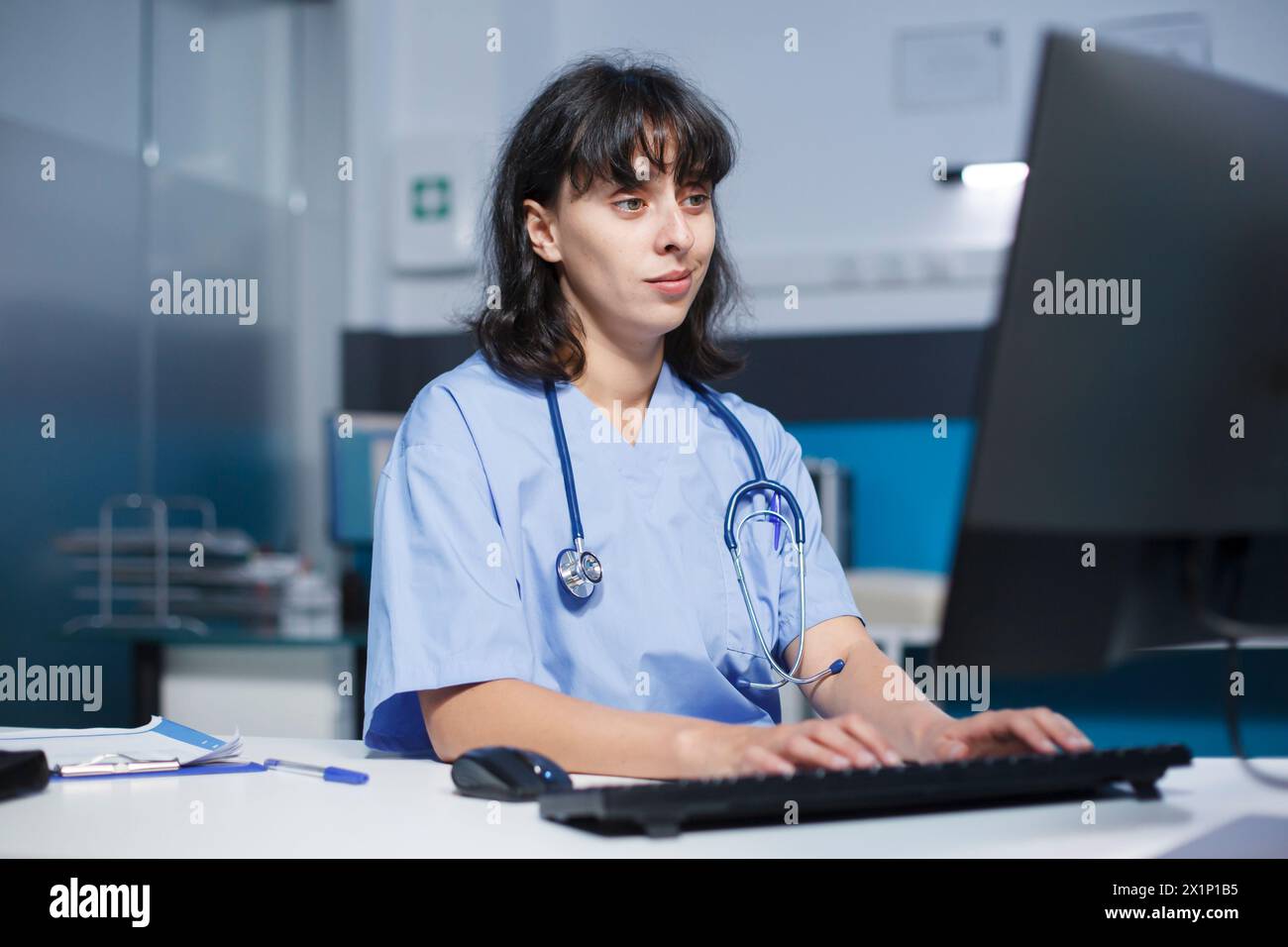 Female practitioner in a modern clinic office using a keyboard to type ...