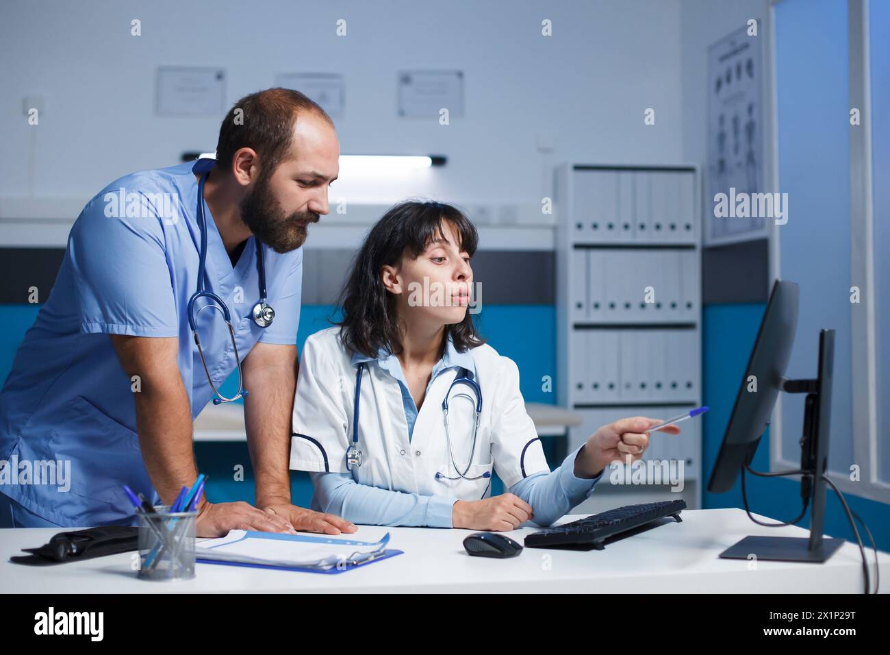 Caucasian medical staff in blue scrubs and lab coat collaborate ...