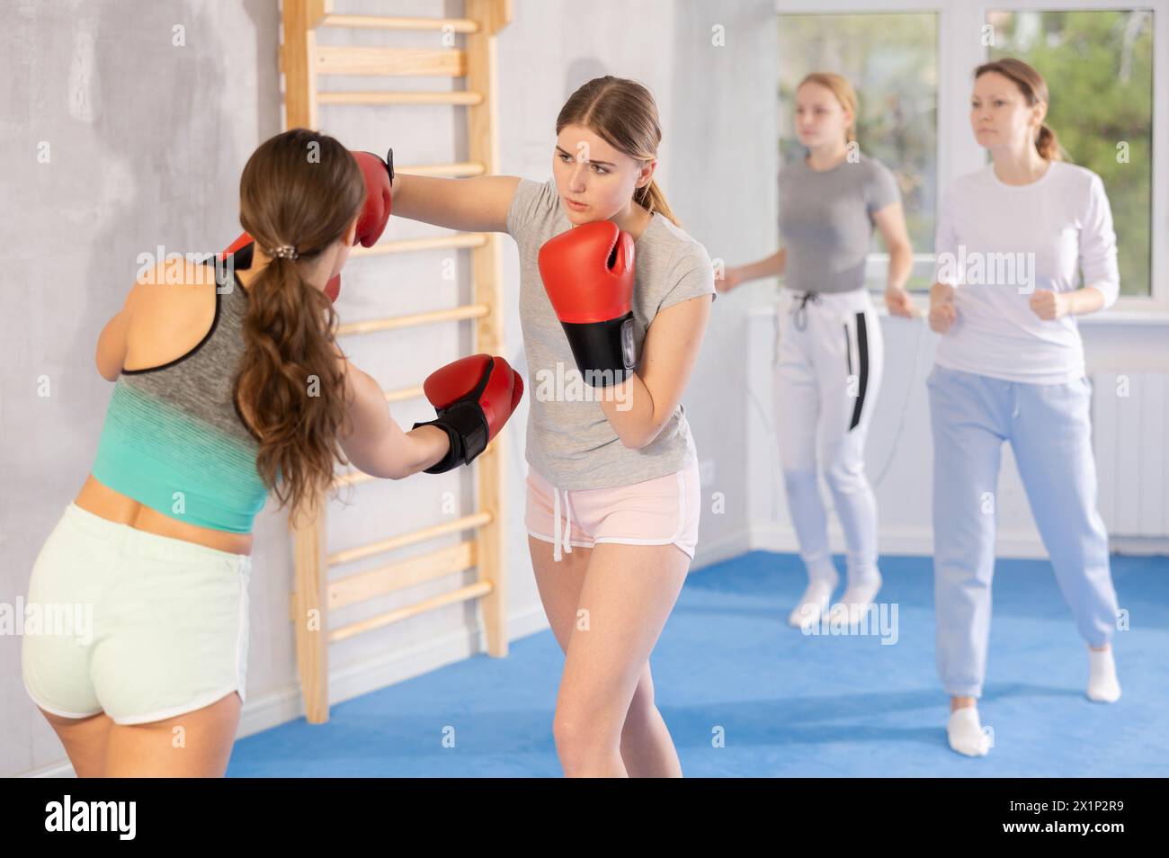 Adolescent girl in boxing gloves practicing punches in sparring during self defence course Stock ...